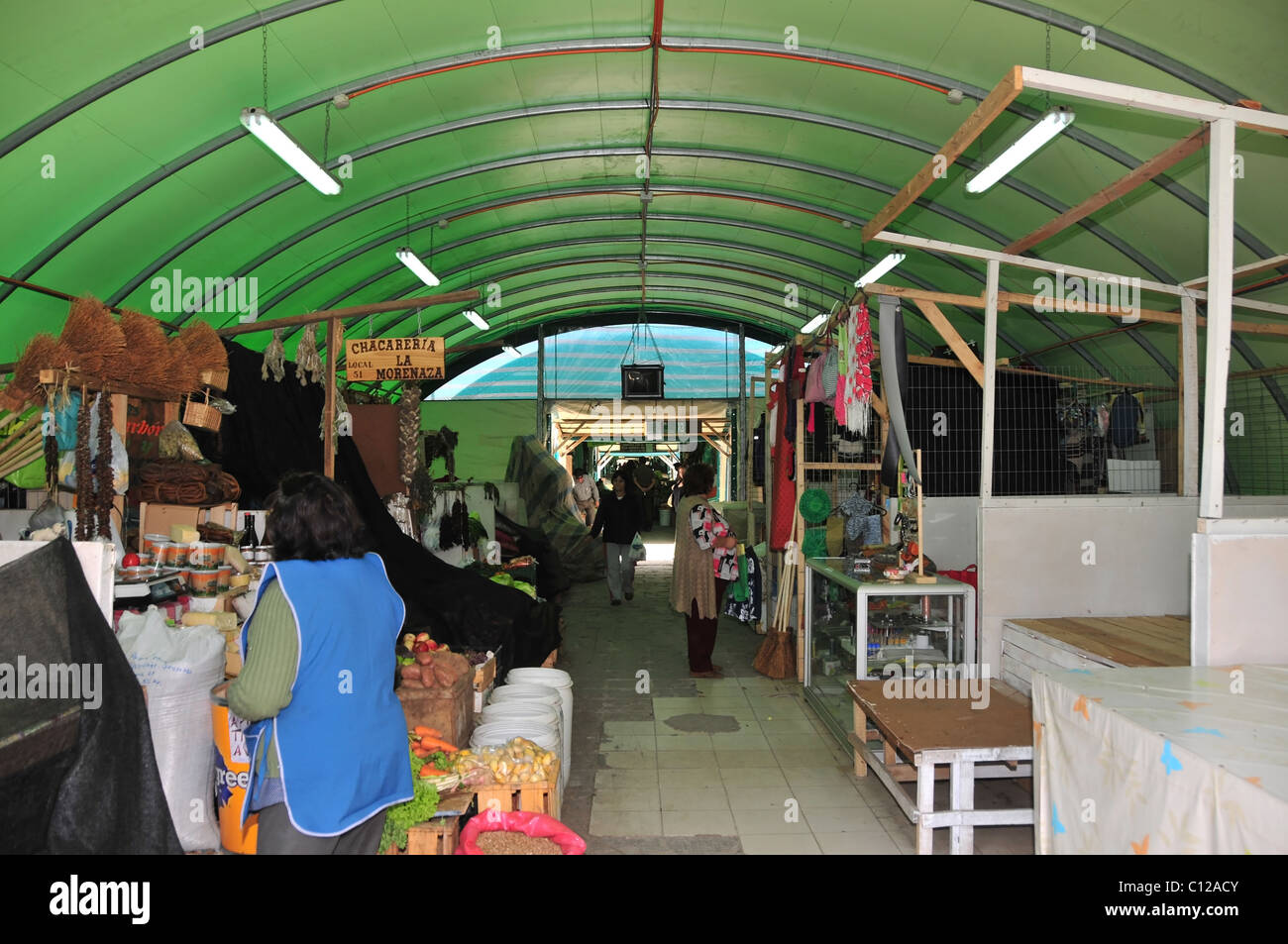 Indoor market stalls, with lady shop-keeper, selling fruit vegetables ...