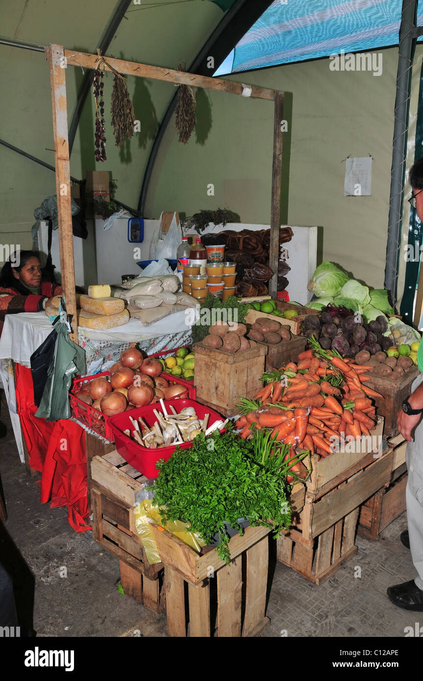 Lady shopkeeper sitting behind vegetables seaweed smoked mussels indoor ...