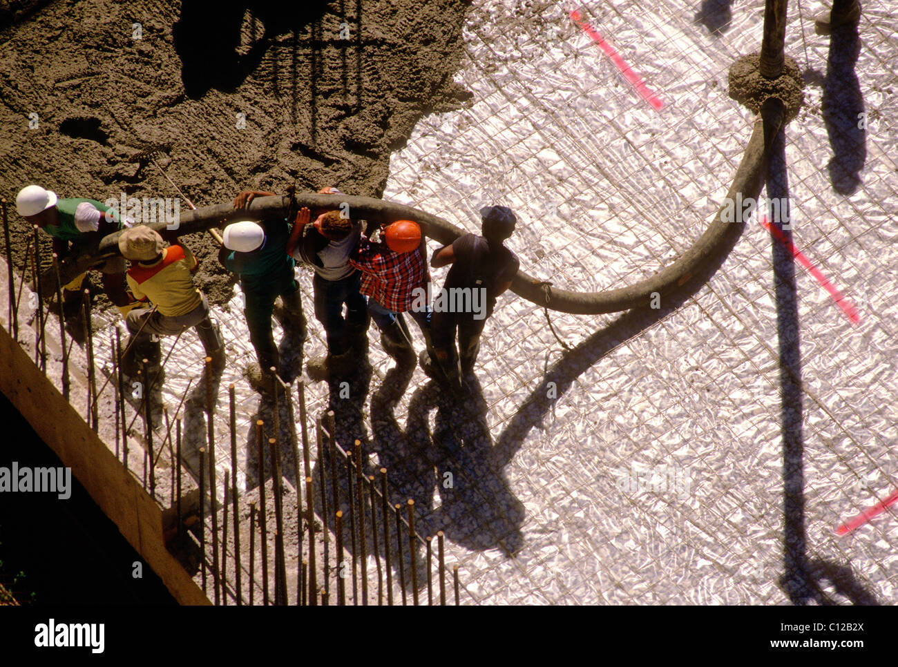 Construction workers position a heavy pipe to pour cement at a ...