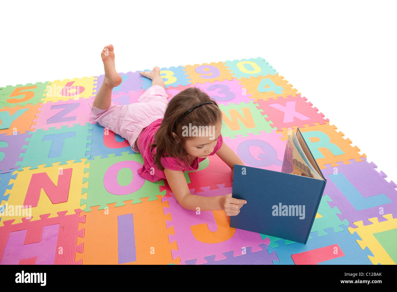 Girl reading book on colorful alphabet floor mat. Isolated on white ...