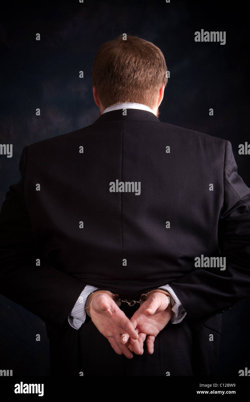 Businessman in suit is handcuffed behind his back Stock Photo - Alamy