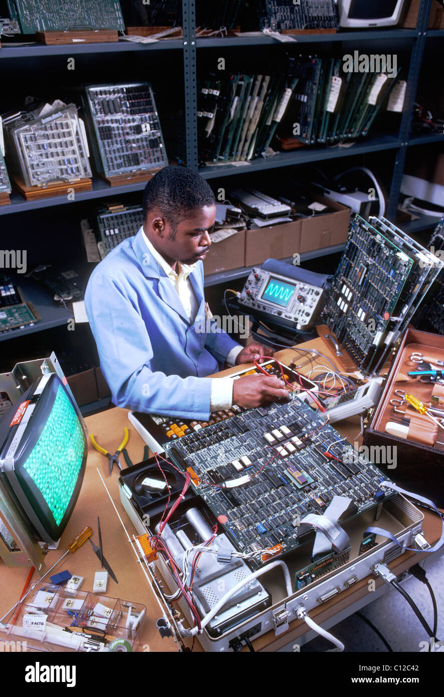 African American technician inspects printed circuit boards at a ...