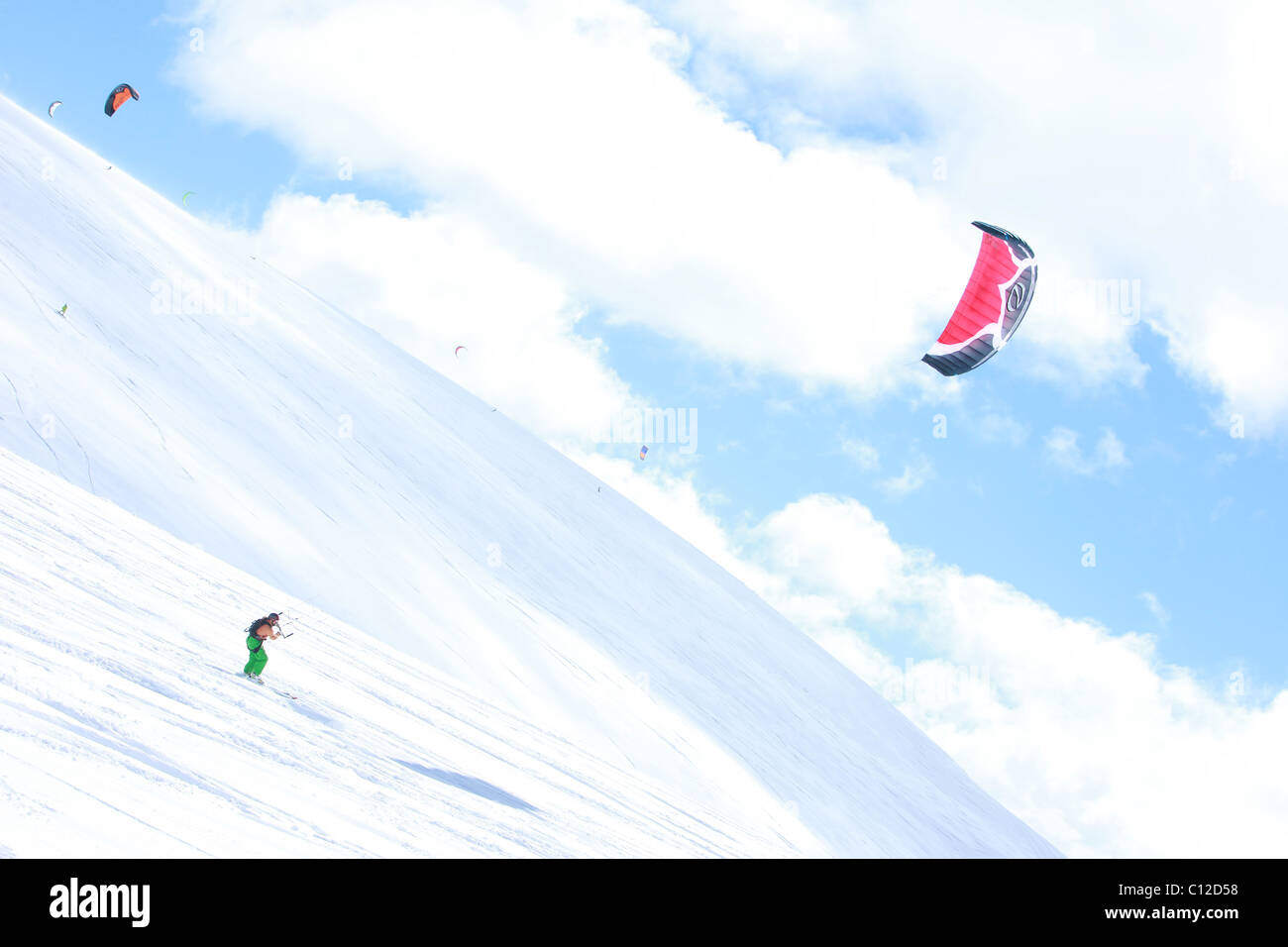 Snowkite riding in the mountains of Utah. Bright yellow sail and blue ...