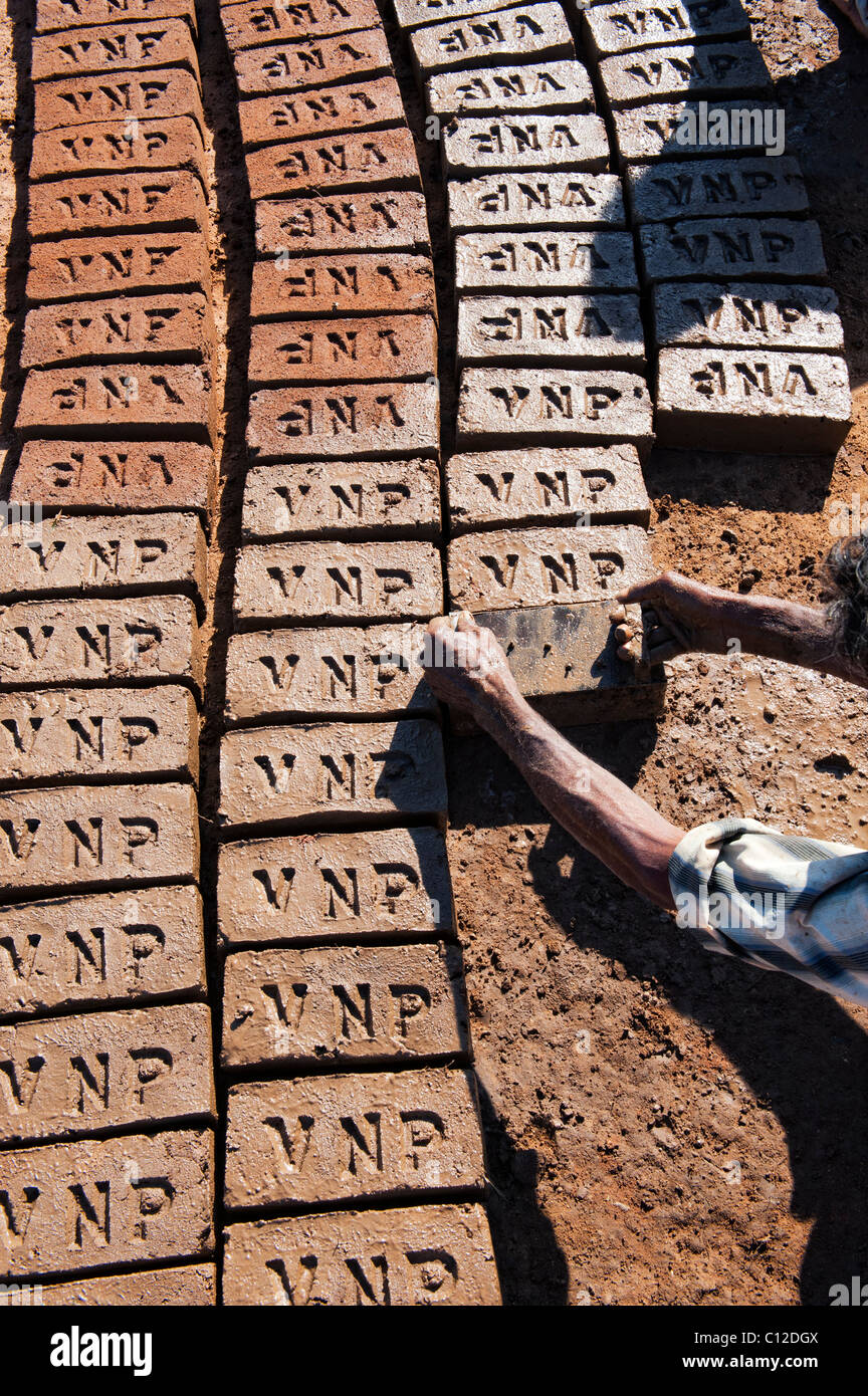 Indian men making house bricks by hand using a mould and wet clay / mud ...