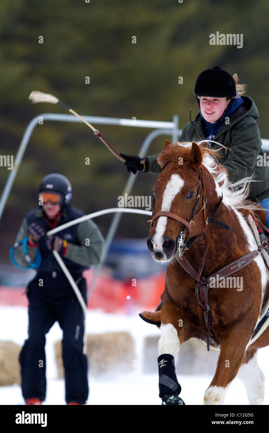 Horse and rider running in the snow while towing a skier during a ski ...