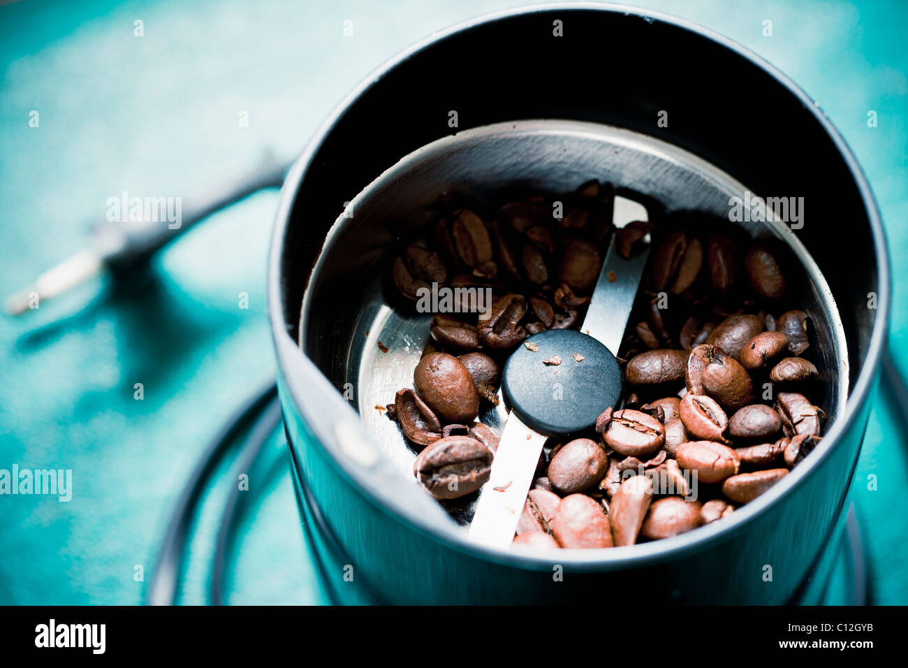 Electrical coffee-mill machine with roasted coffee beans on the green ...