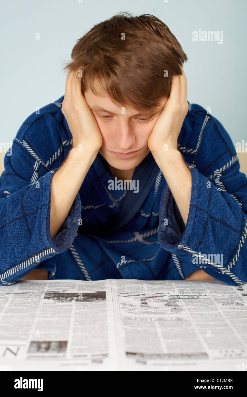 Sad man reading a newspaper at home in his dressing gown Stock Photo ...