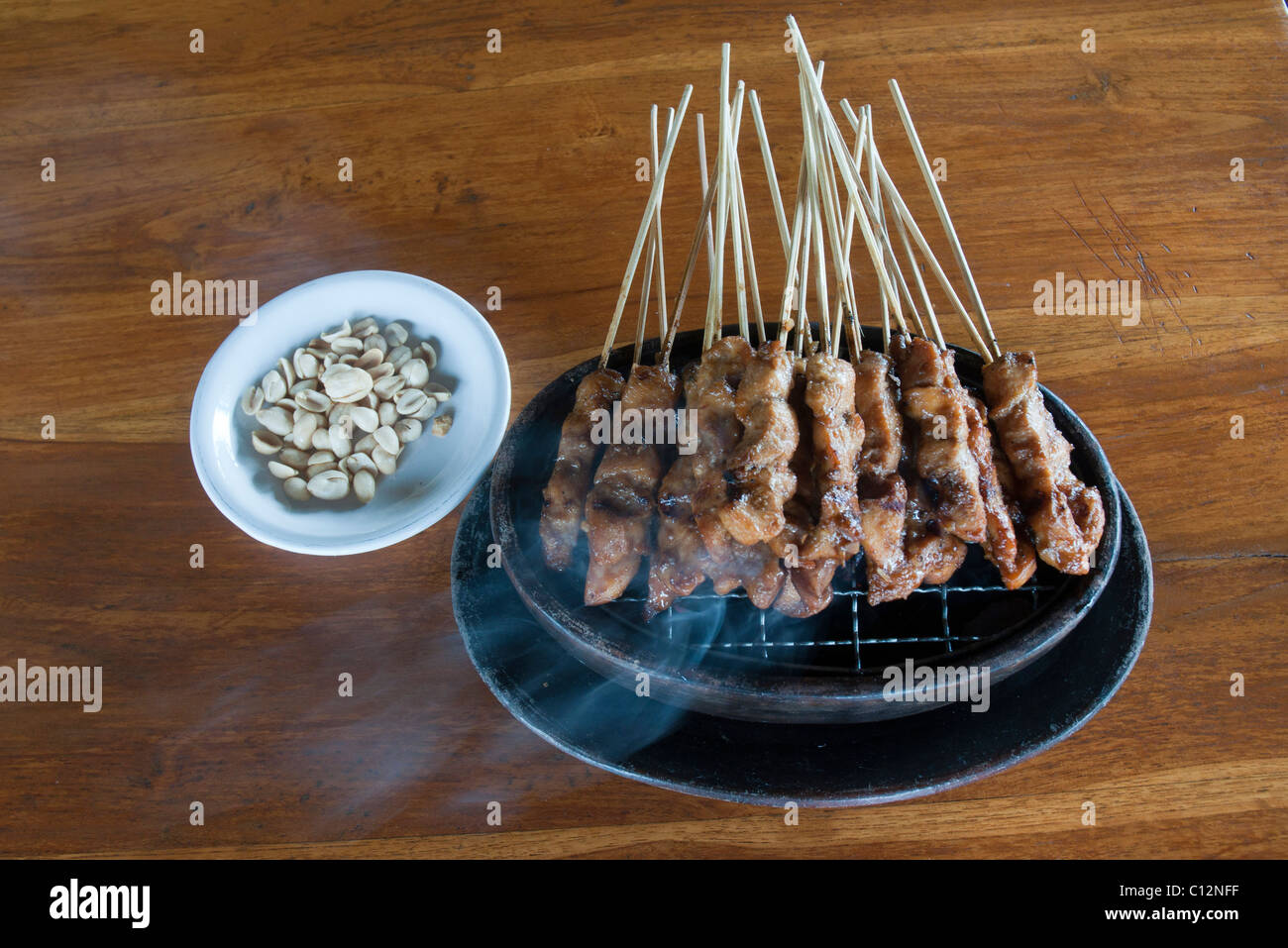 Chicken satay cooking at the table on a miniature charcoal grill in ...