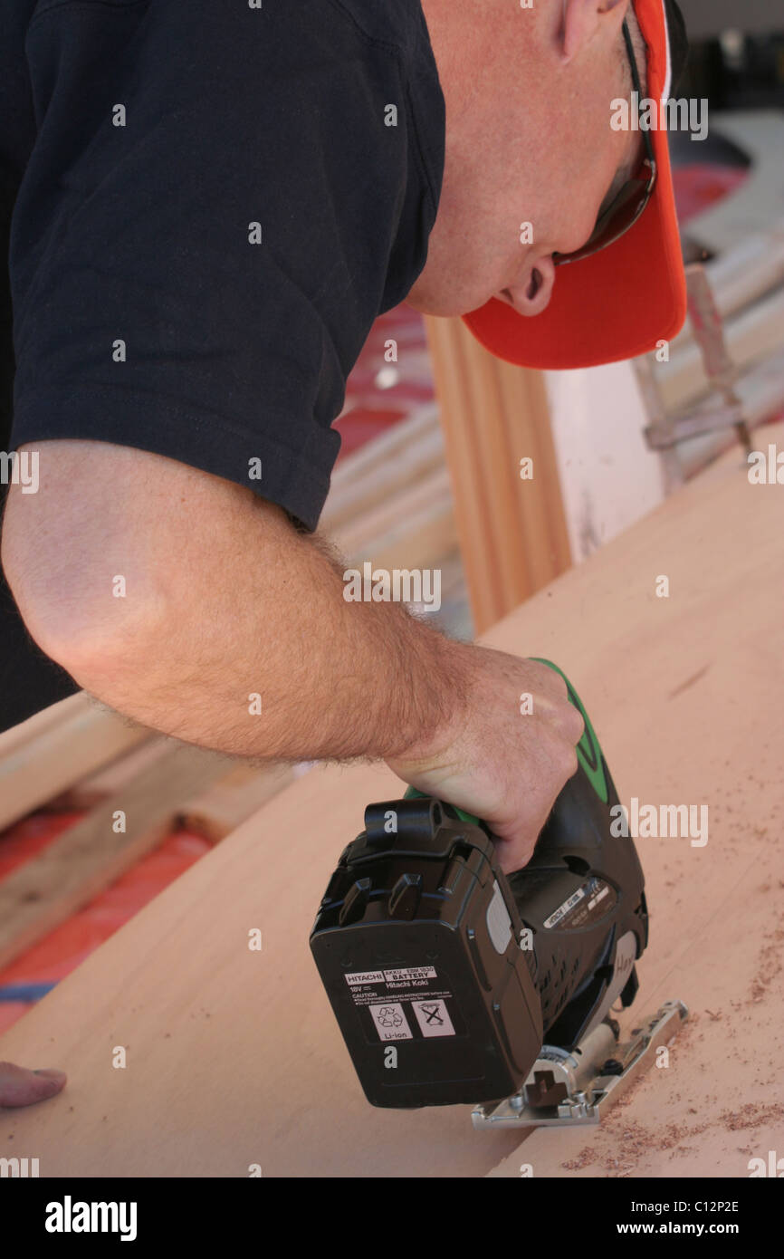 Carpenter cutting timber with an electric jigsaw, one of the ...