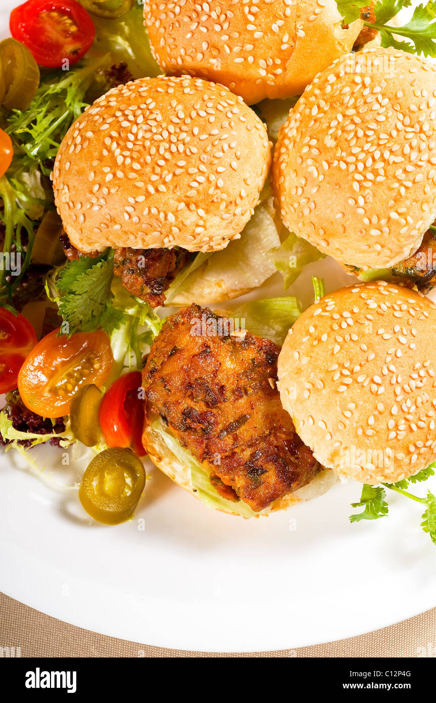 four fresh and delicious mini chicken burgers on a plate ,close up ...