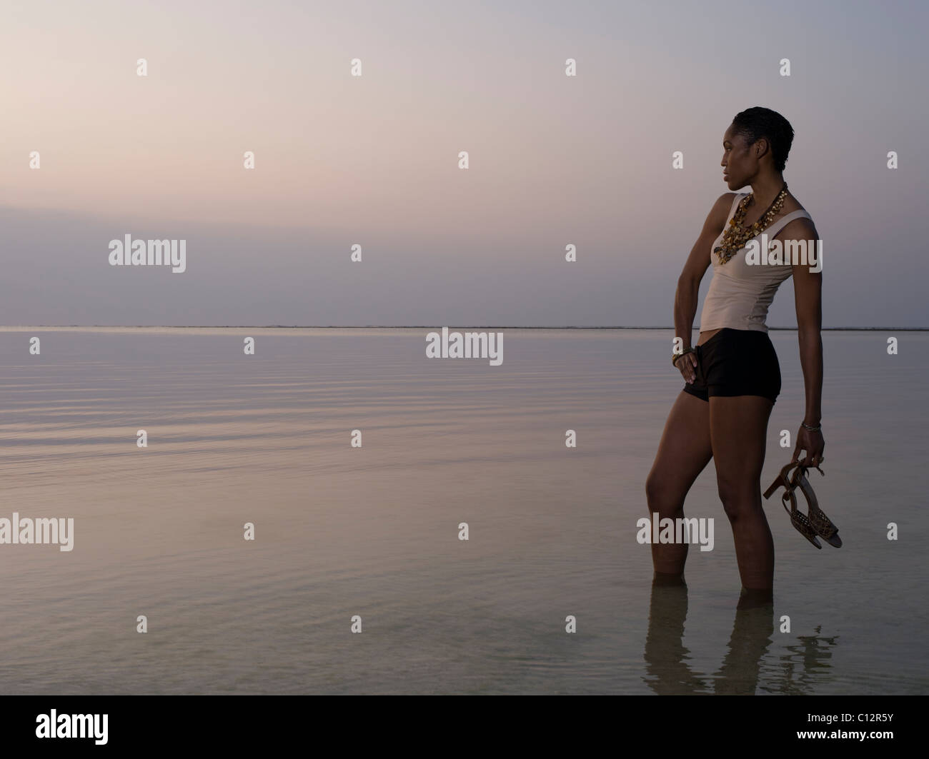Woman wading in the water by the beach. Sunset Stock Photo - Alamy