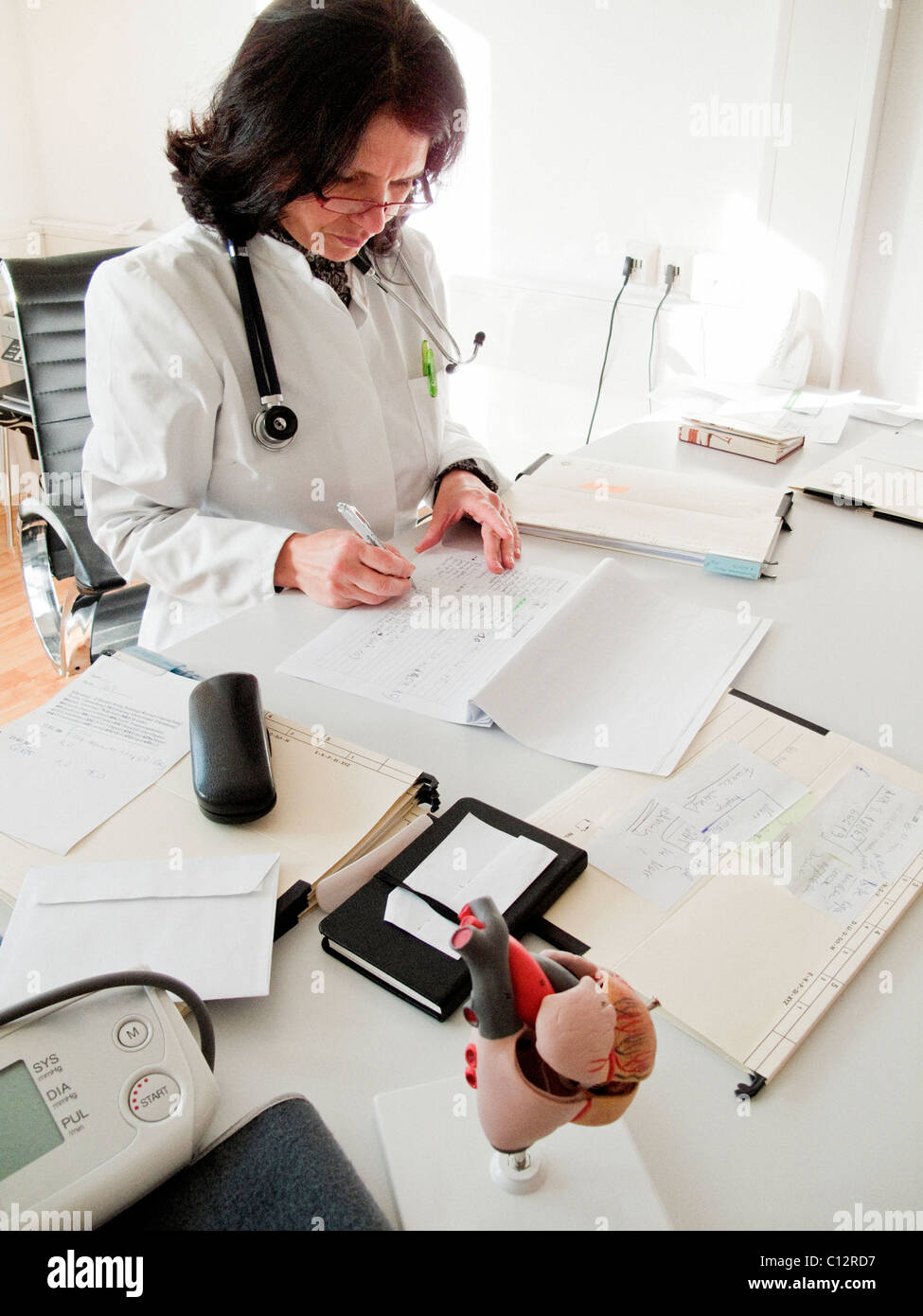 Doctor reading patients files at her desk Stock Photo - Alamy