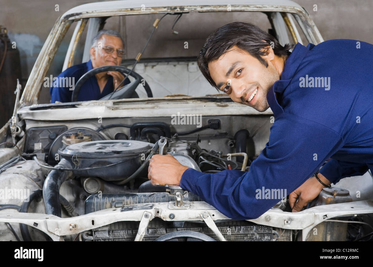 Auto mechanic with an apprentice repairing a car in a garage Stock ...