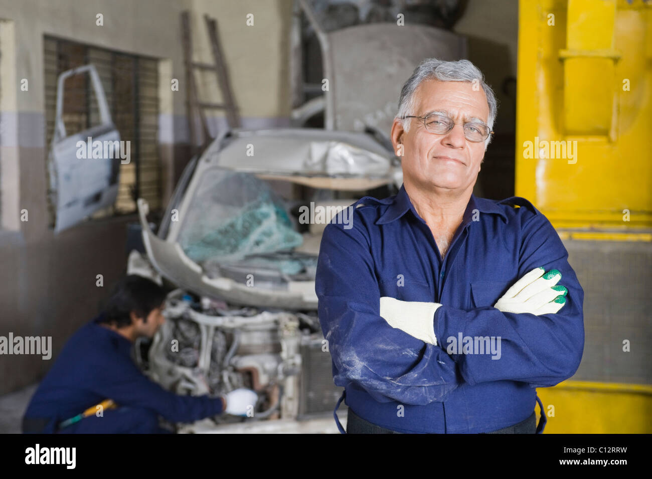 Portrait of an auto mechanic with an apprentice repairing a car in the ...