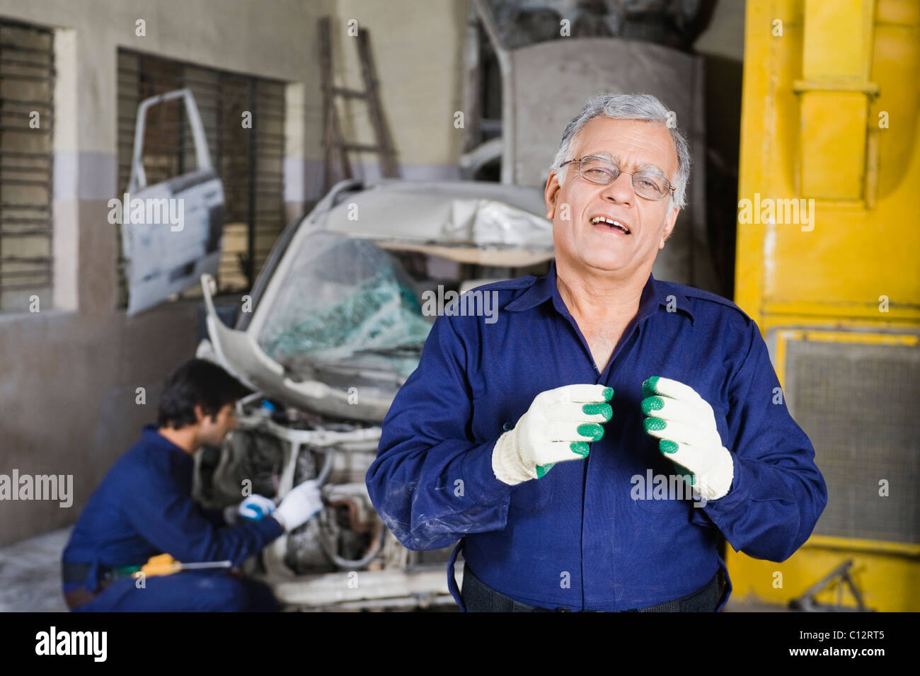 Portrait of an auto mechanic with an apprentice repairing a car in the ...