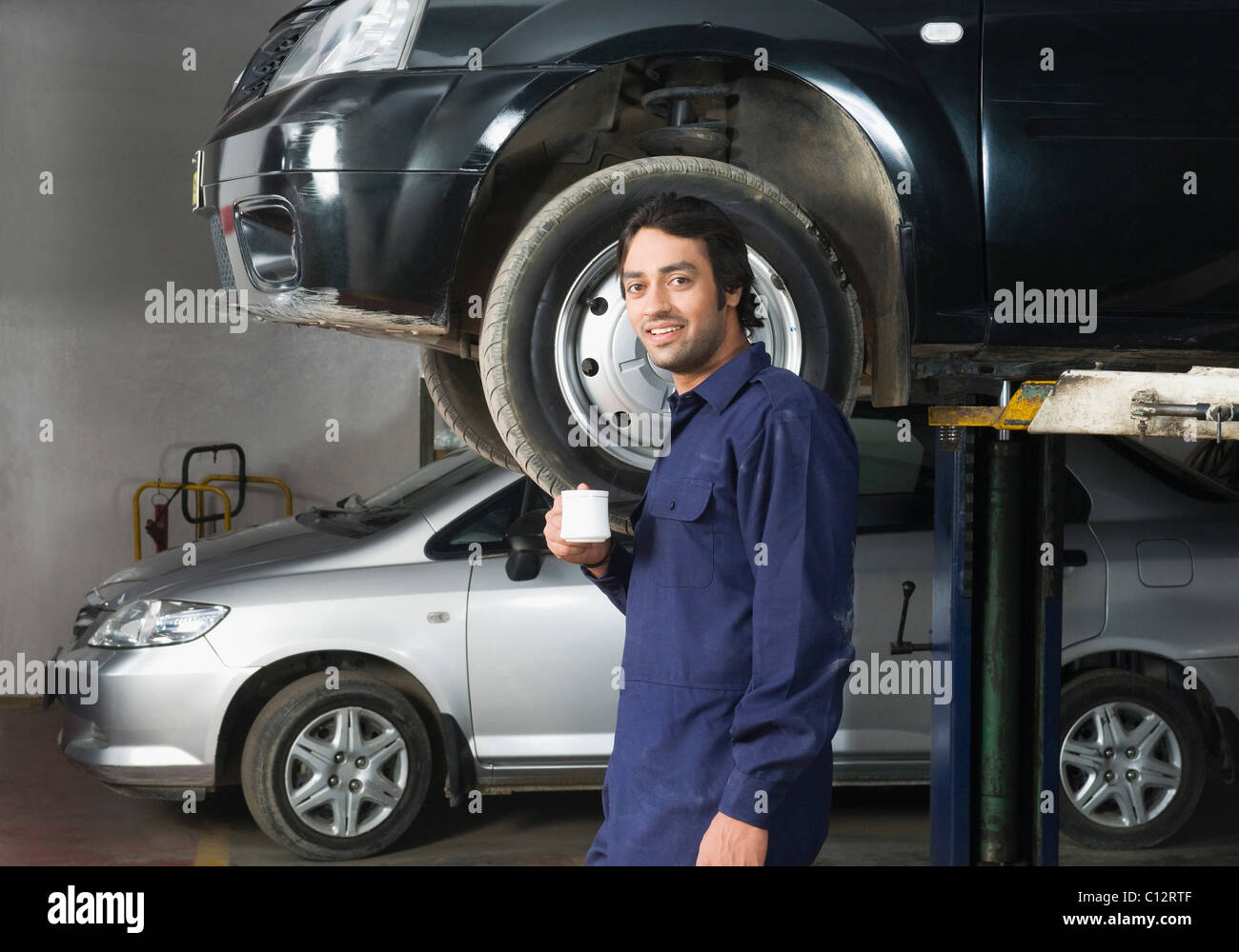 Portrait of an auto mechanic holding a cup of coffee in a garage Stock ...