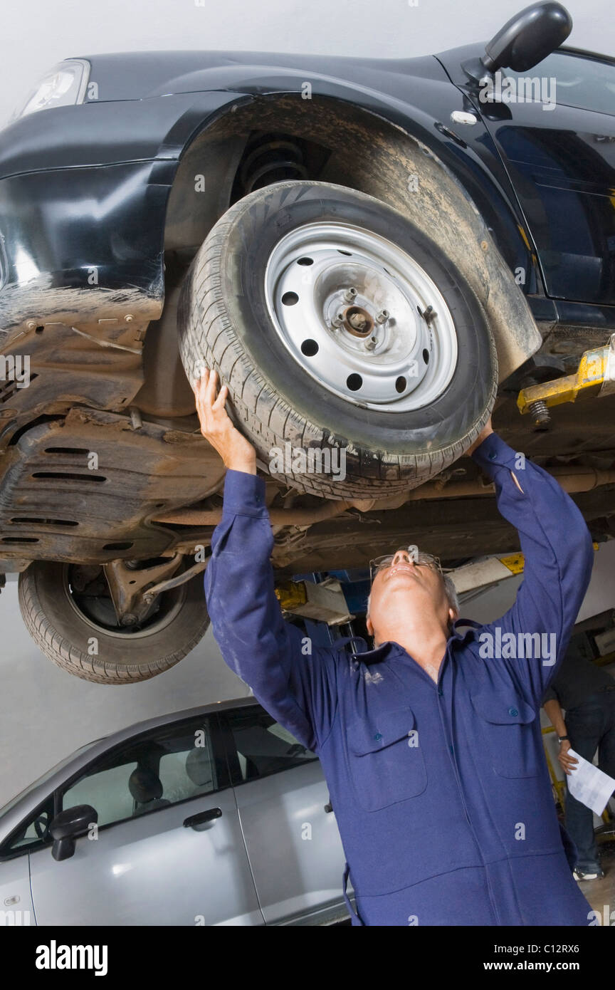 Auto mechanic working on a car wheel in a garage Stock Photo - Alamy