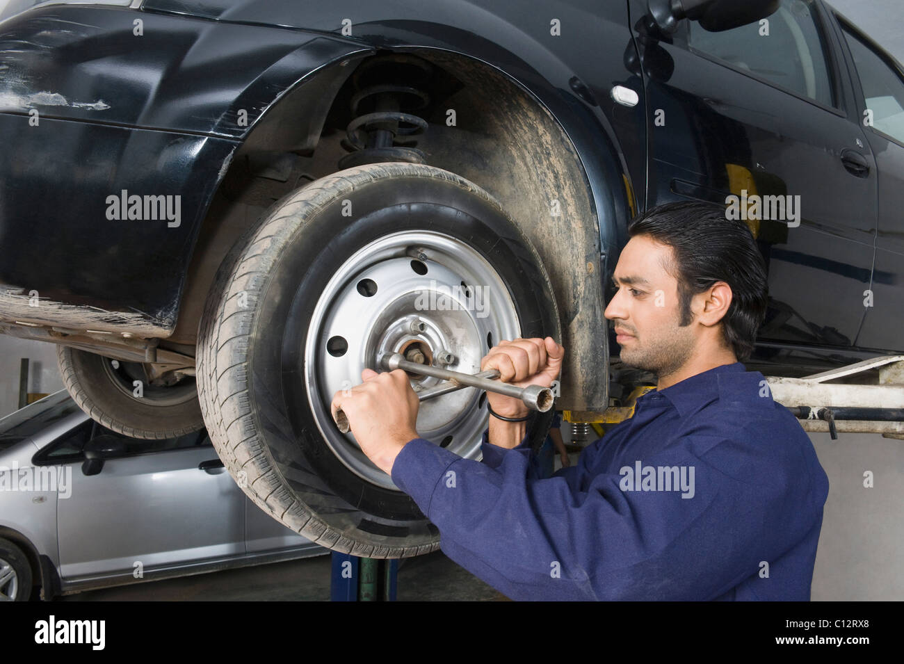 Auto mechanic working on a car wheel in a garage Stock Photo - Alamy