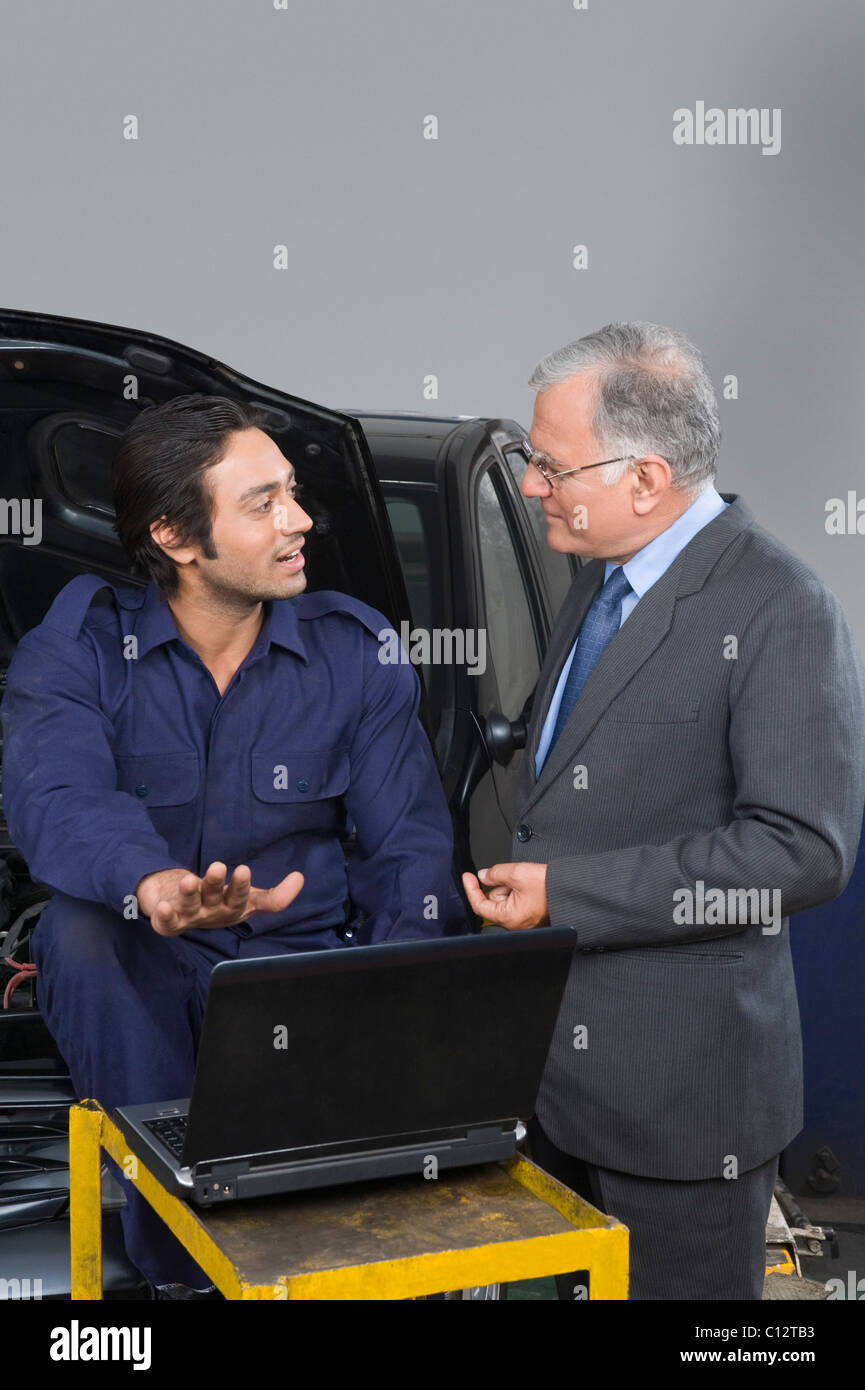 Auto mechanic talking to a customer while using a laptop Stock Photo ...