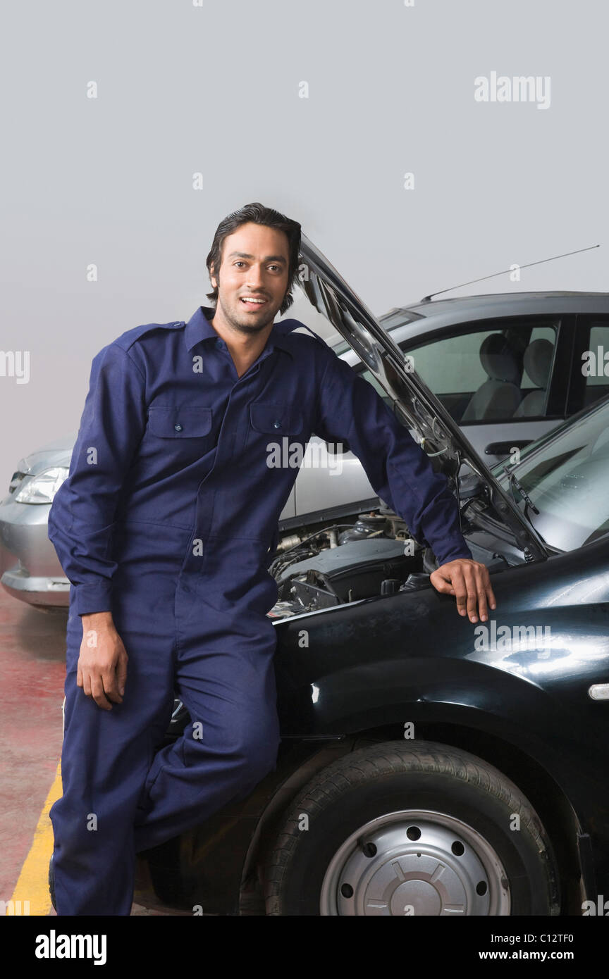 Auto mechanic leaning on a car in a garage Stock Photo - Alamy