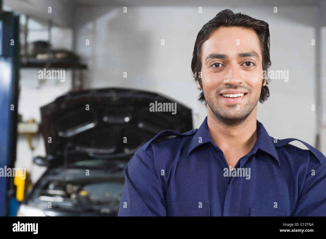 Portrait of an auto mechanic smiling with a car in the background Stock ...