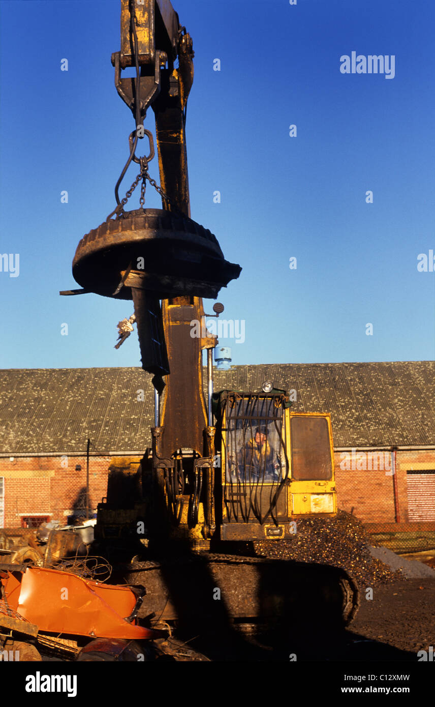 magnetic arm of crane carrying scrap metal into trailer for recycling ...