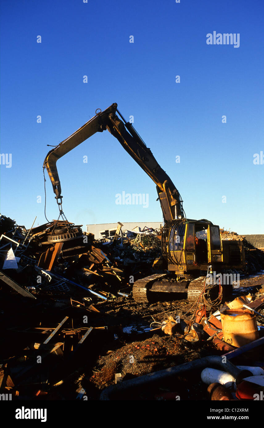 magnetic arm of crane carrying scrap metal into trailer for recycling ...
