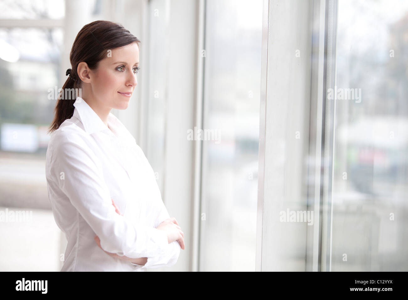 portrait of young woman standing at window Stock Photo - Alamy