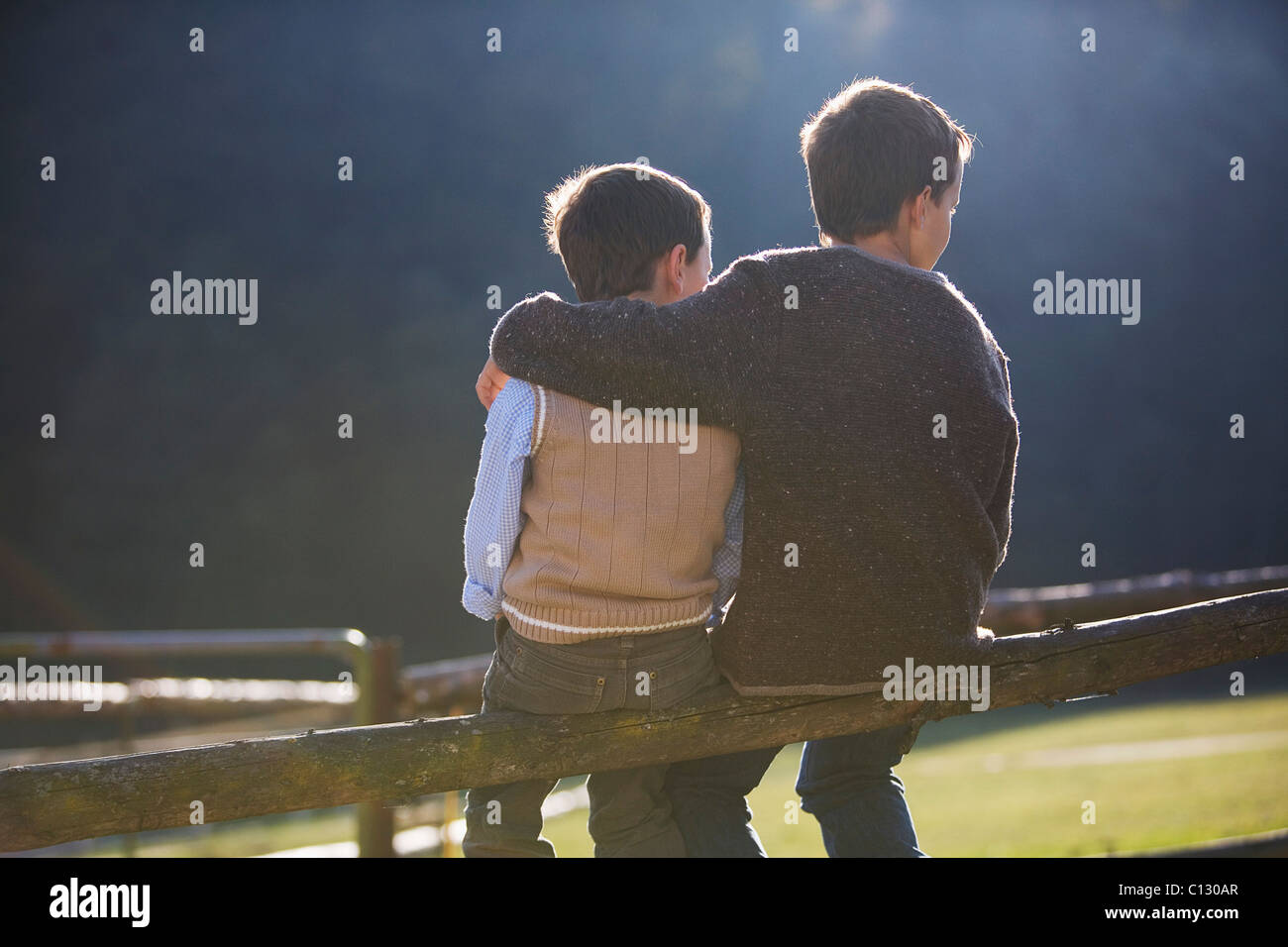 rear view of two boys sitting fence Stock Photo - Alamy