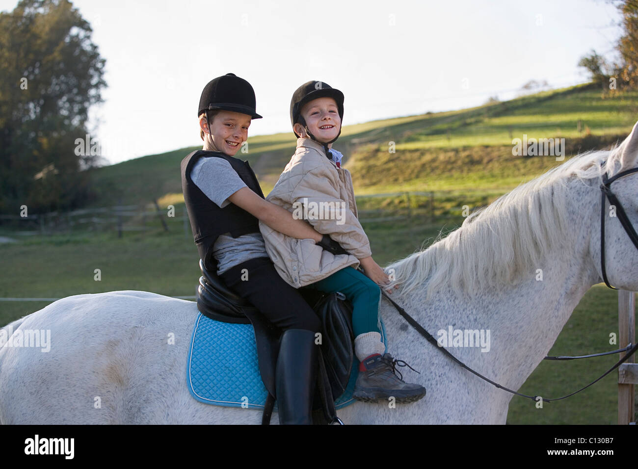 portrait of two young boys sitting on white horse Stock Photo - Alamy