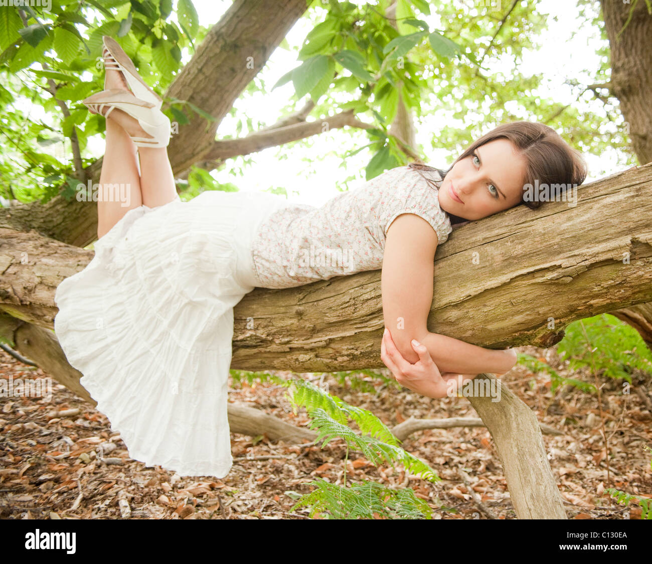 portrait of young woman lying on tree trunk Stock Photo - Alamy