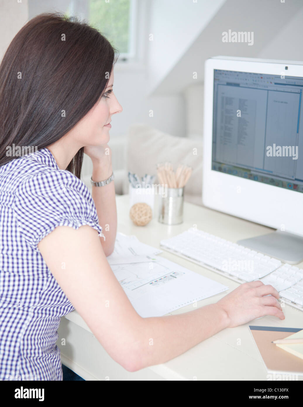 young woman at home looking at computer screen Stock Photo - Alamy
