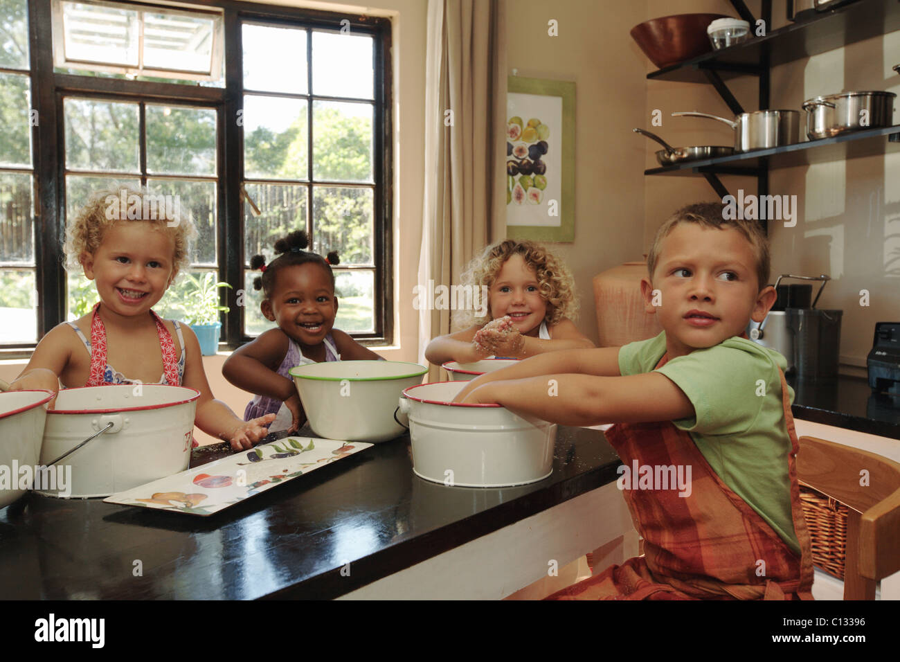 Boys and girls (4-5, 2-3, 18-23 months) making food around table, Cape ...