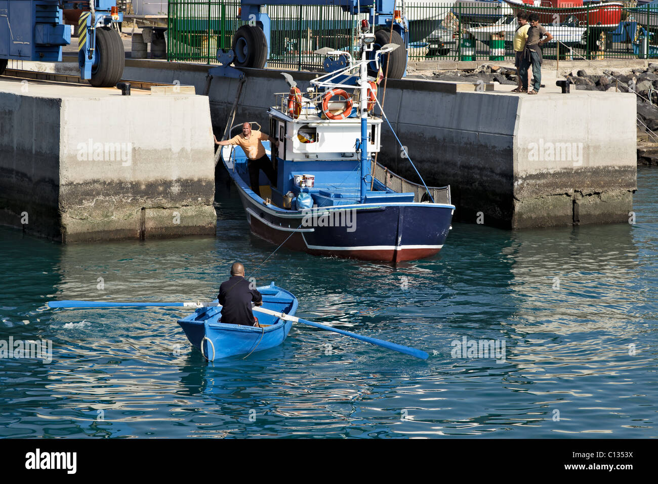 Rowing fishing boat to side of harbour Stock Photo - Alamy