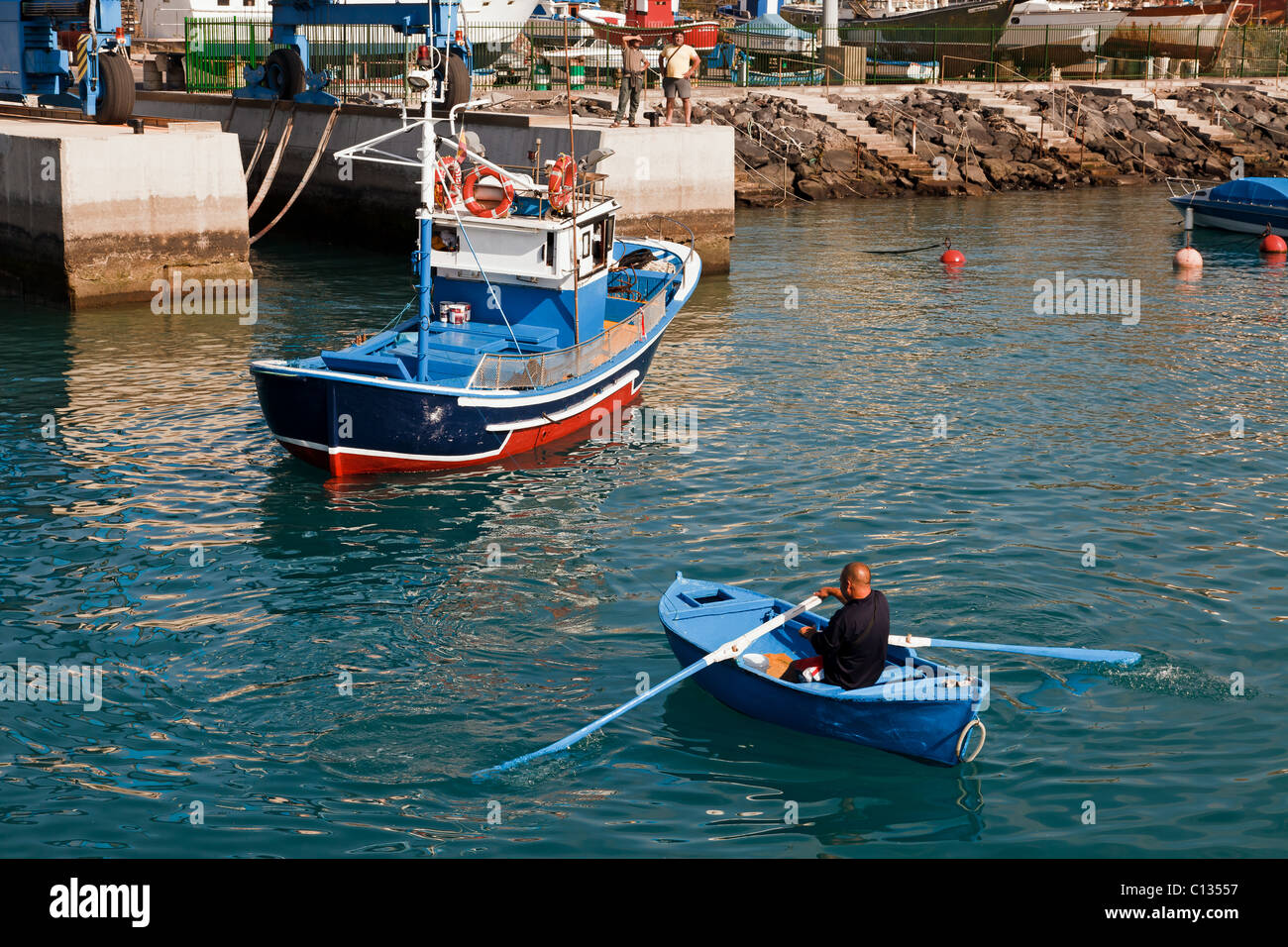 Rowing fishing boat to side of harbour Stock Photo - Alamy