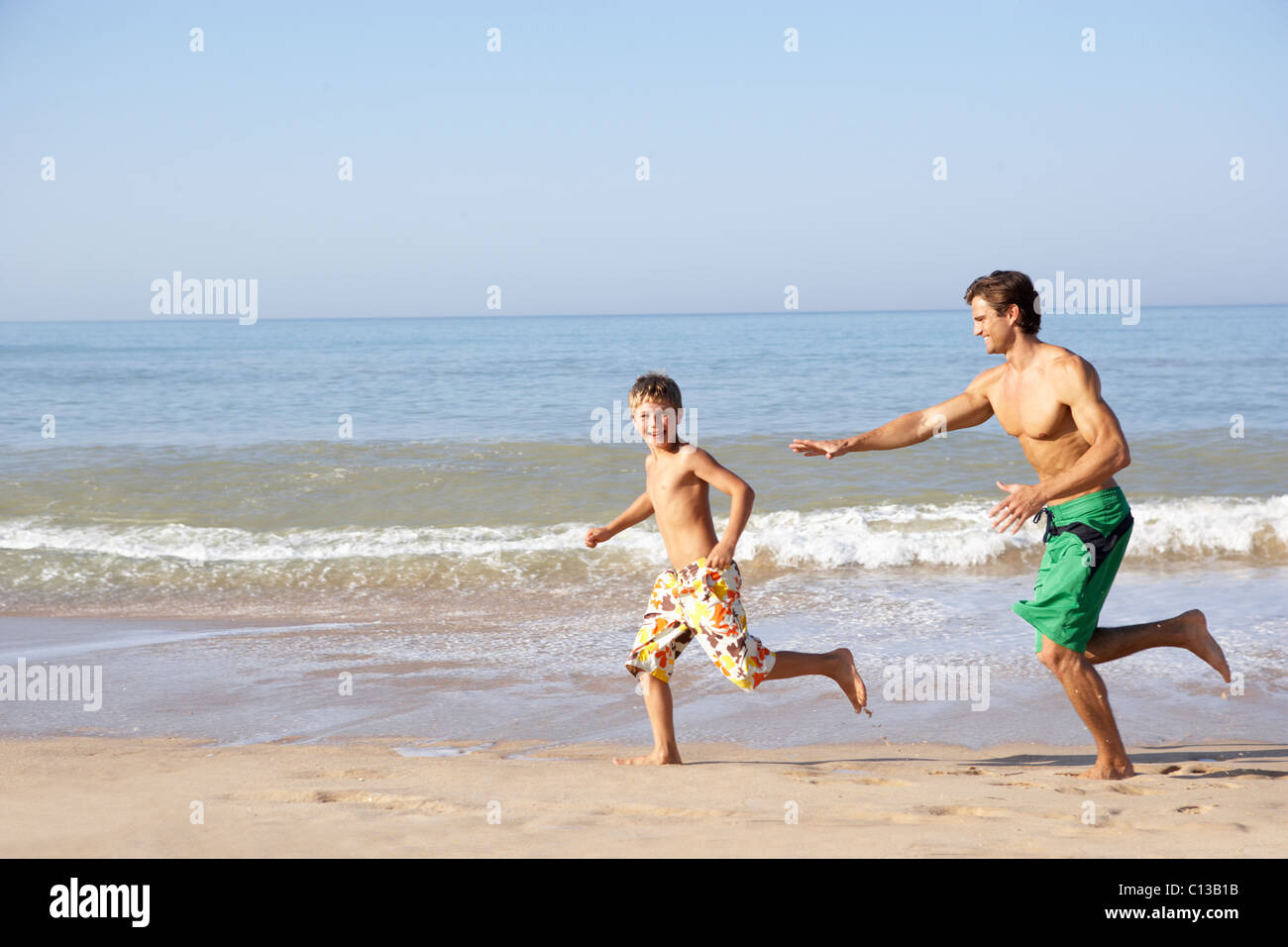 Father chasing young boy on beach Stock Photo - Alamy