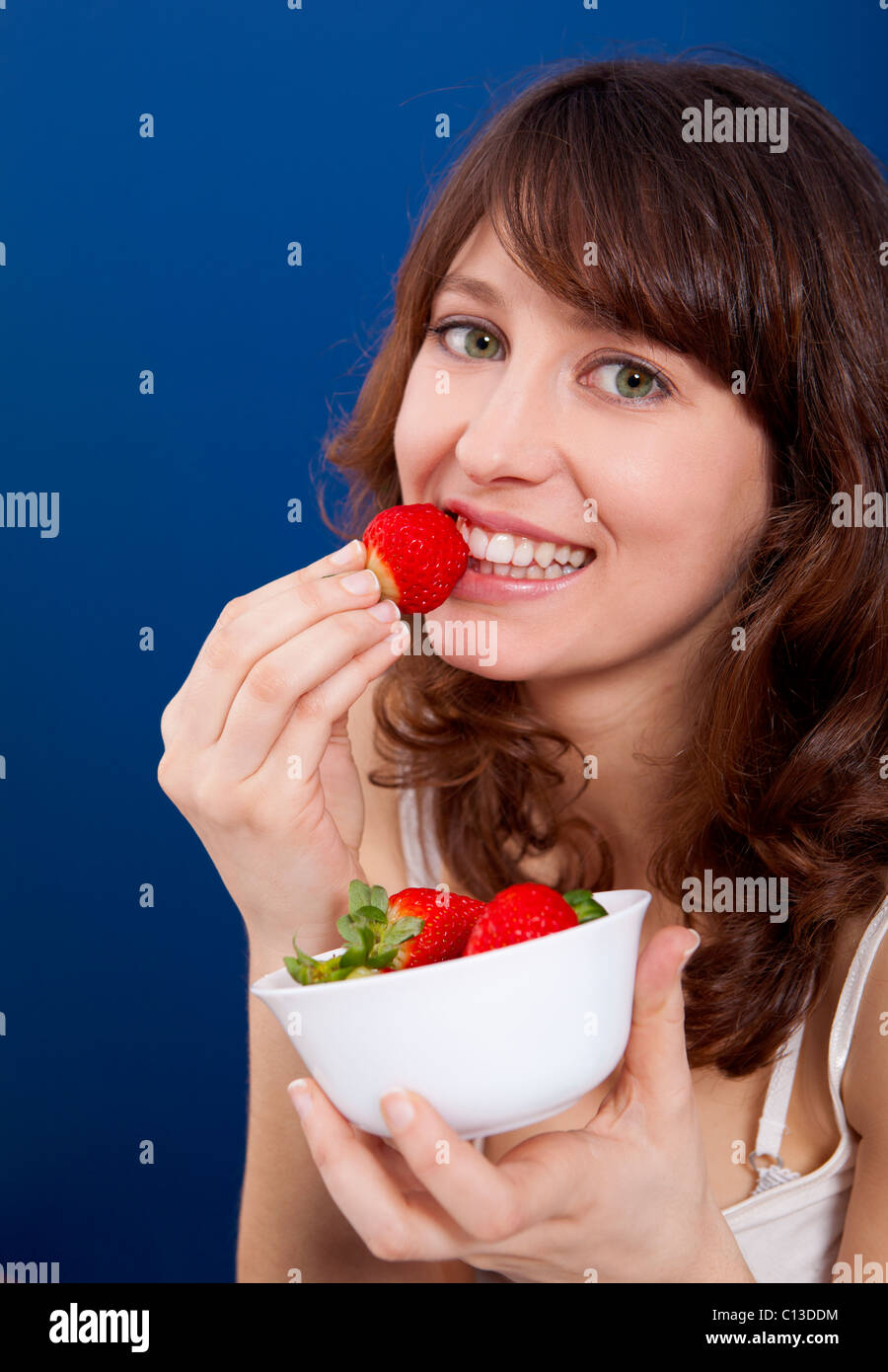 Beautiful and happy young woman eating strawberries Stock Photo - Alamy