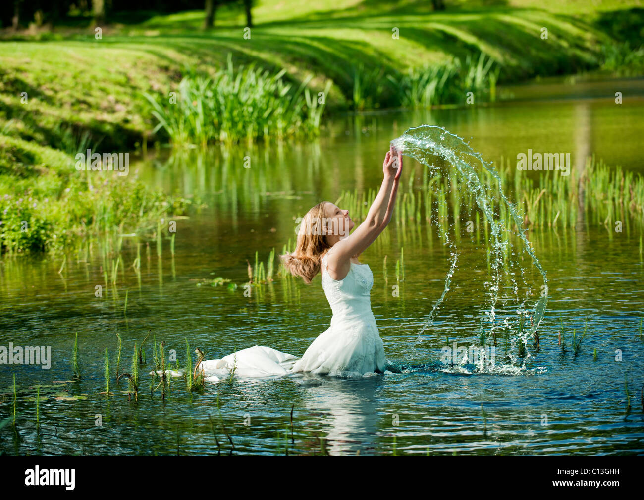 woman lady walking into lake water up to her waist in long wedding ...