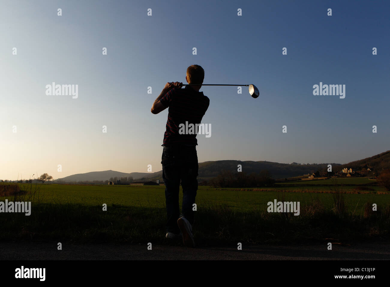 Man playing golf with a scenic landscape surrounding him as the sun ...