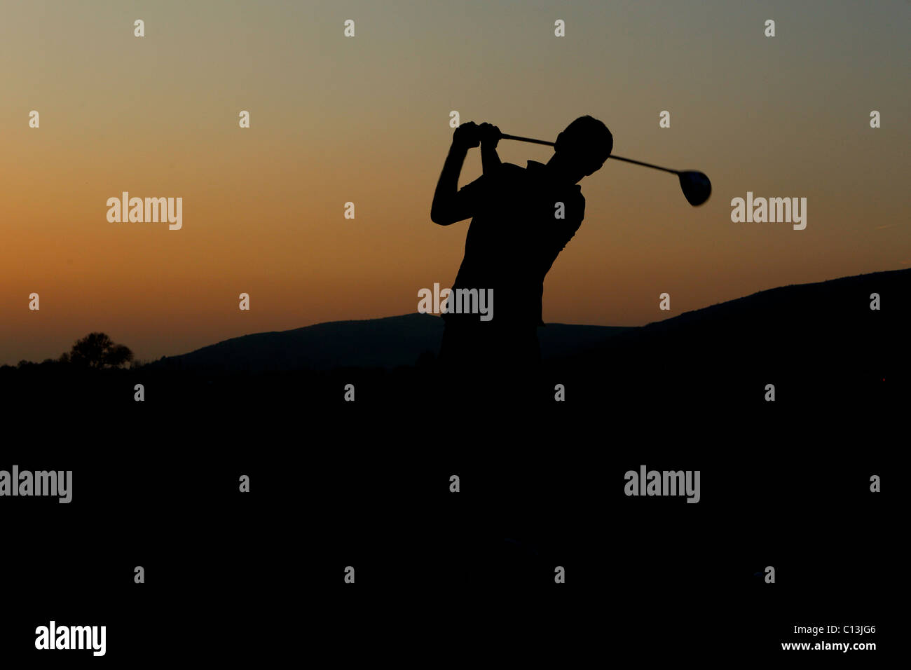 Man playing golf with a scenic landscape surrounding him as the sun ...