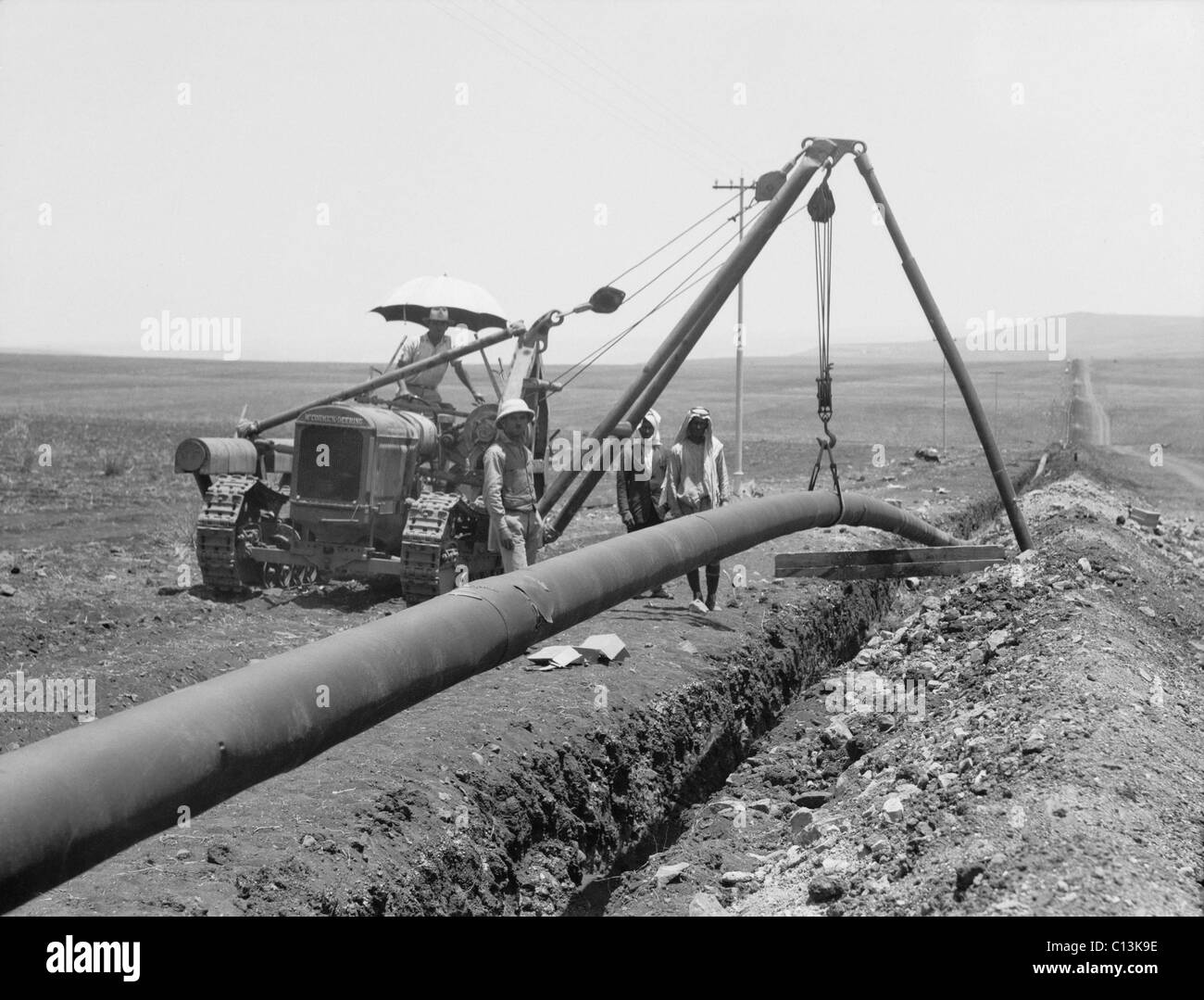 Dropping a welded pipe into a trench with a crane while laying the Iraq ...