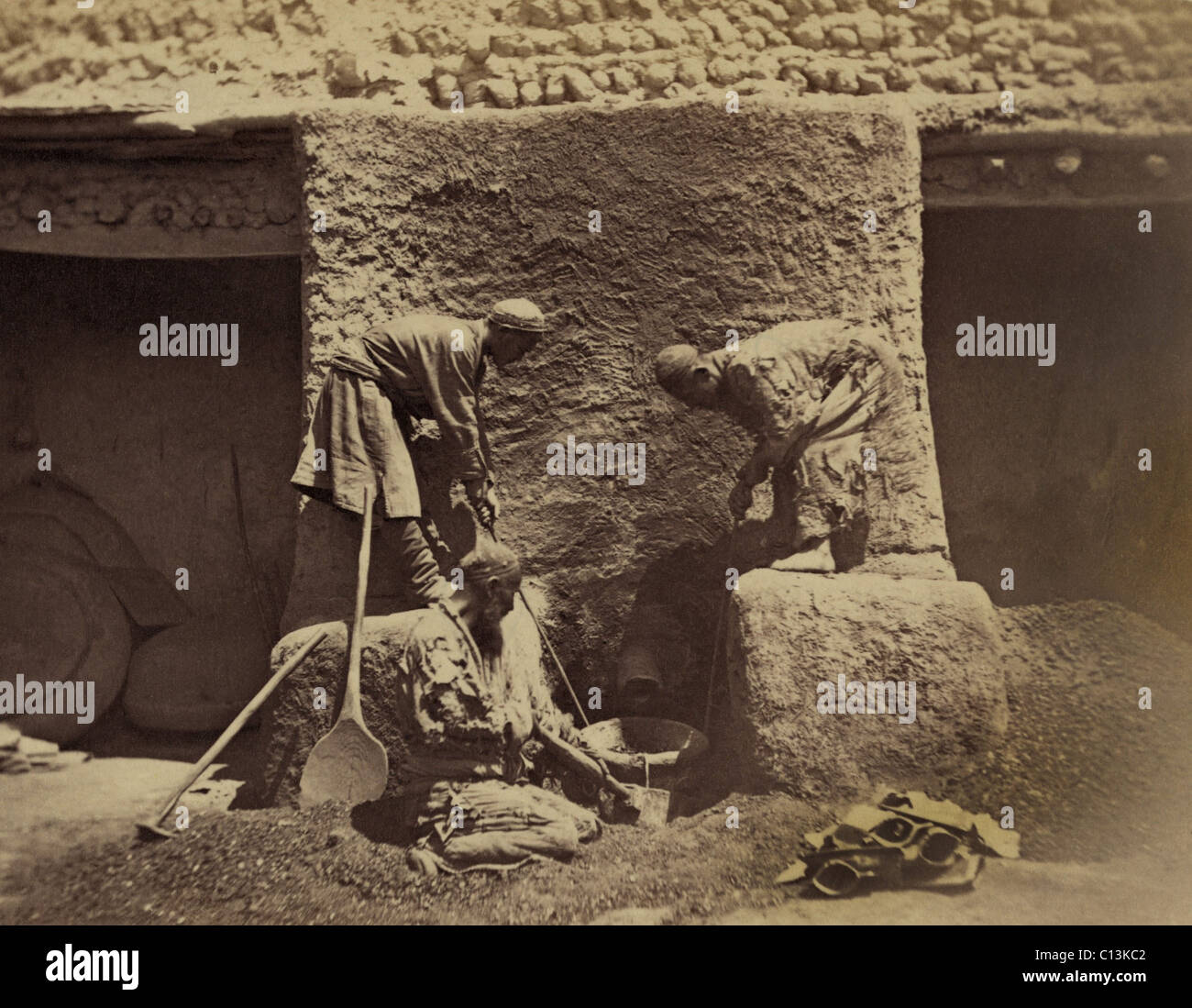 Using centuries old methods, men smelting iron ore in a primitive forge ...