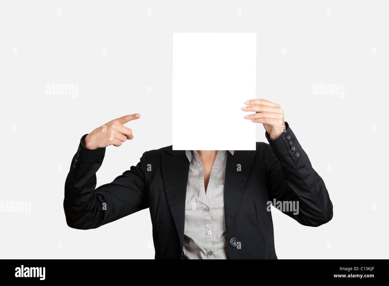 Woman showing and pointing to a blank paper sheet in front of her head ...