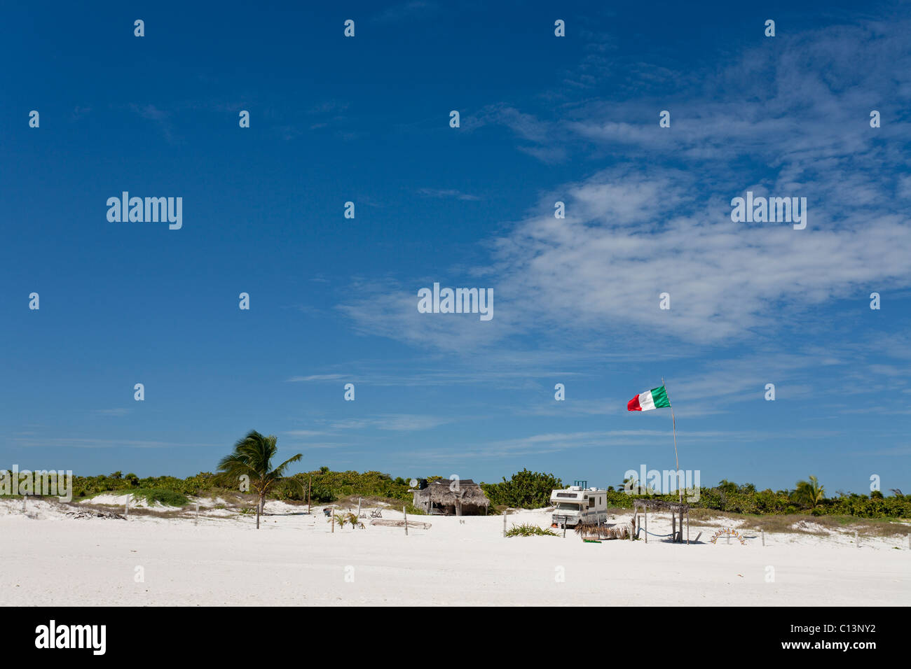 Mexican flag on a stick flag pole at a rustic encampment on the beach ...