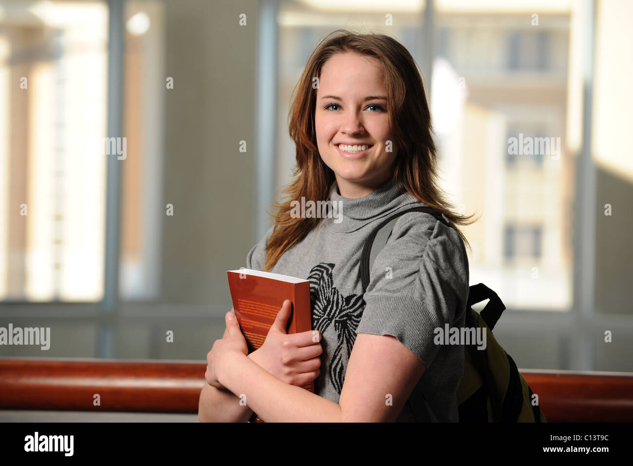 Female student smiling holding books inside building Stock Photo - Alamy