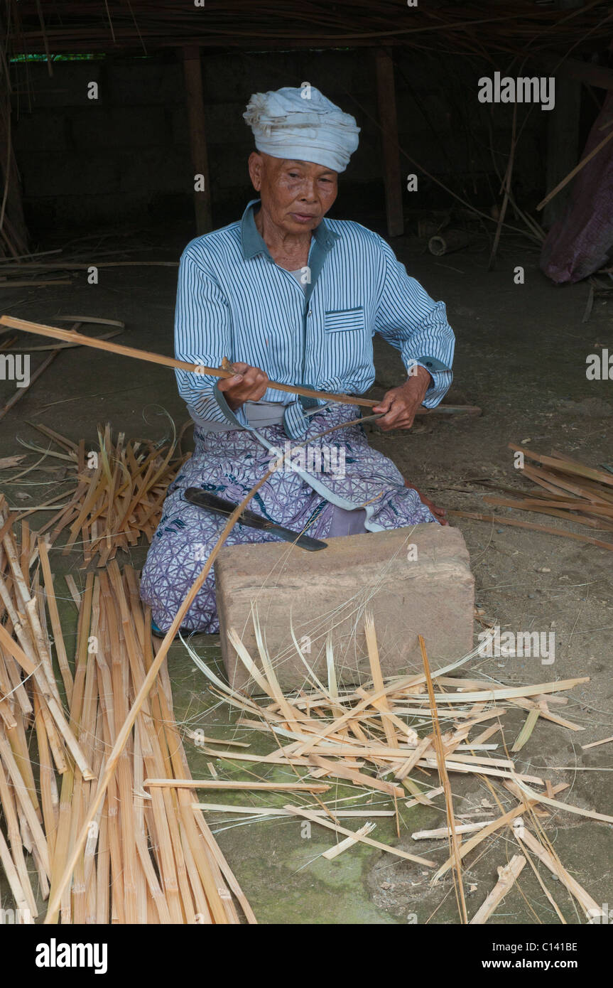 Woman splitting bamboo for weaving into traditional panels for lining ...