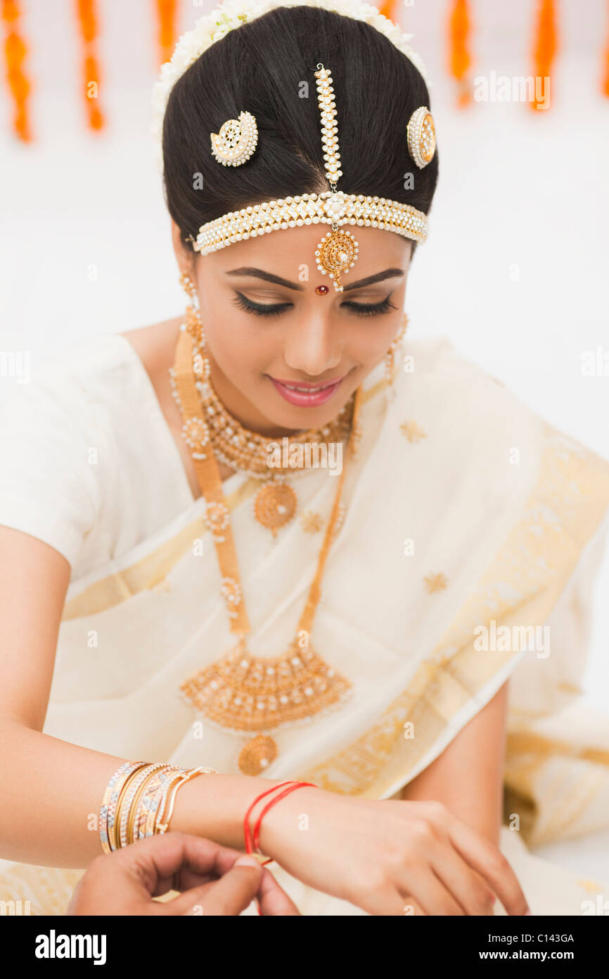 Close-up of a person's hands putting kankanam on a bride's hand Stock ...