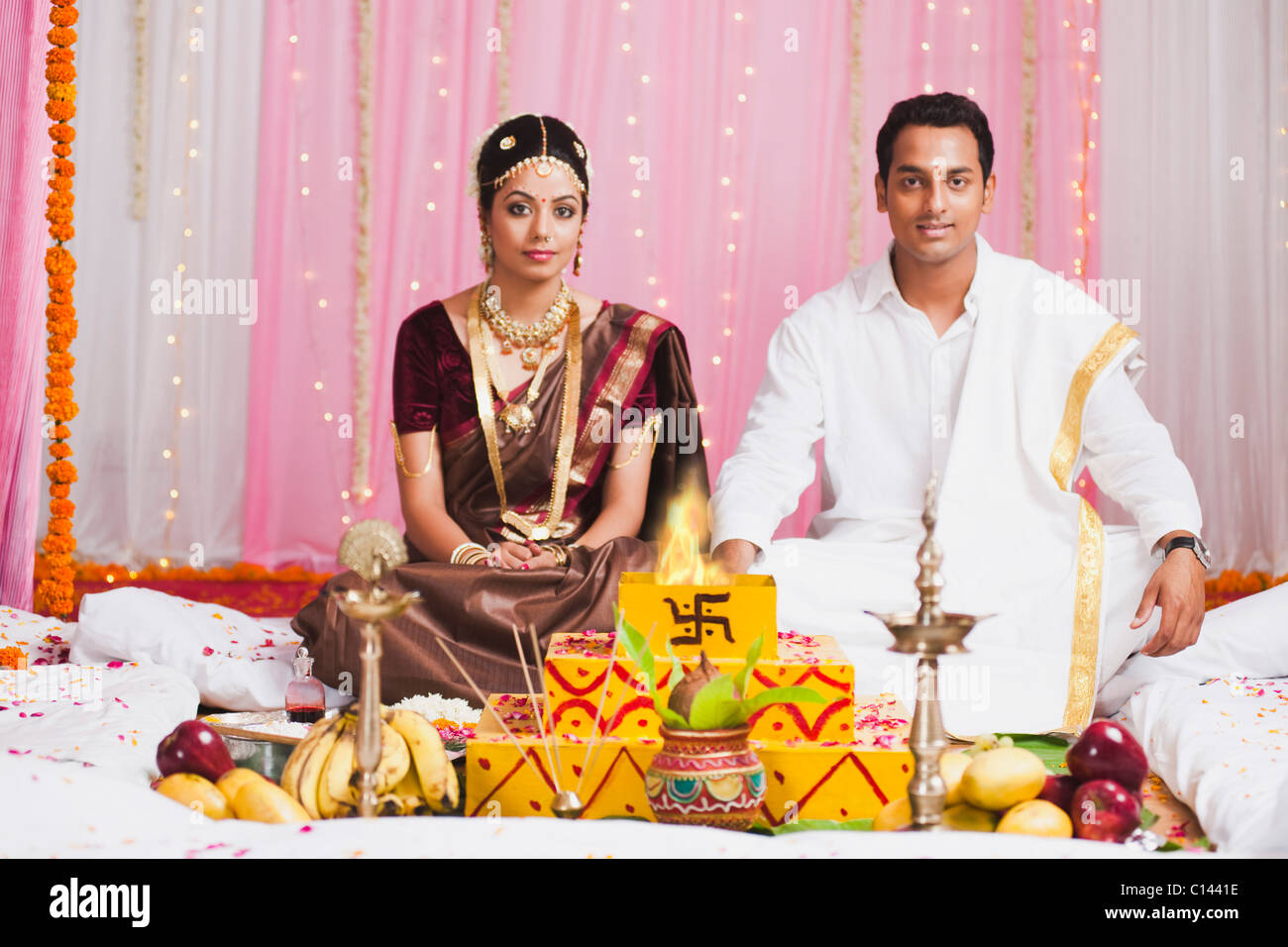 Bride and bridegroom sitting near a havan kund at the wedding mandap ...