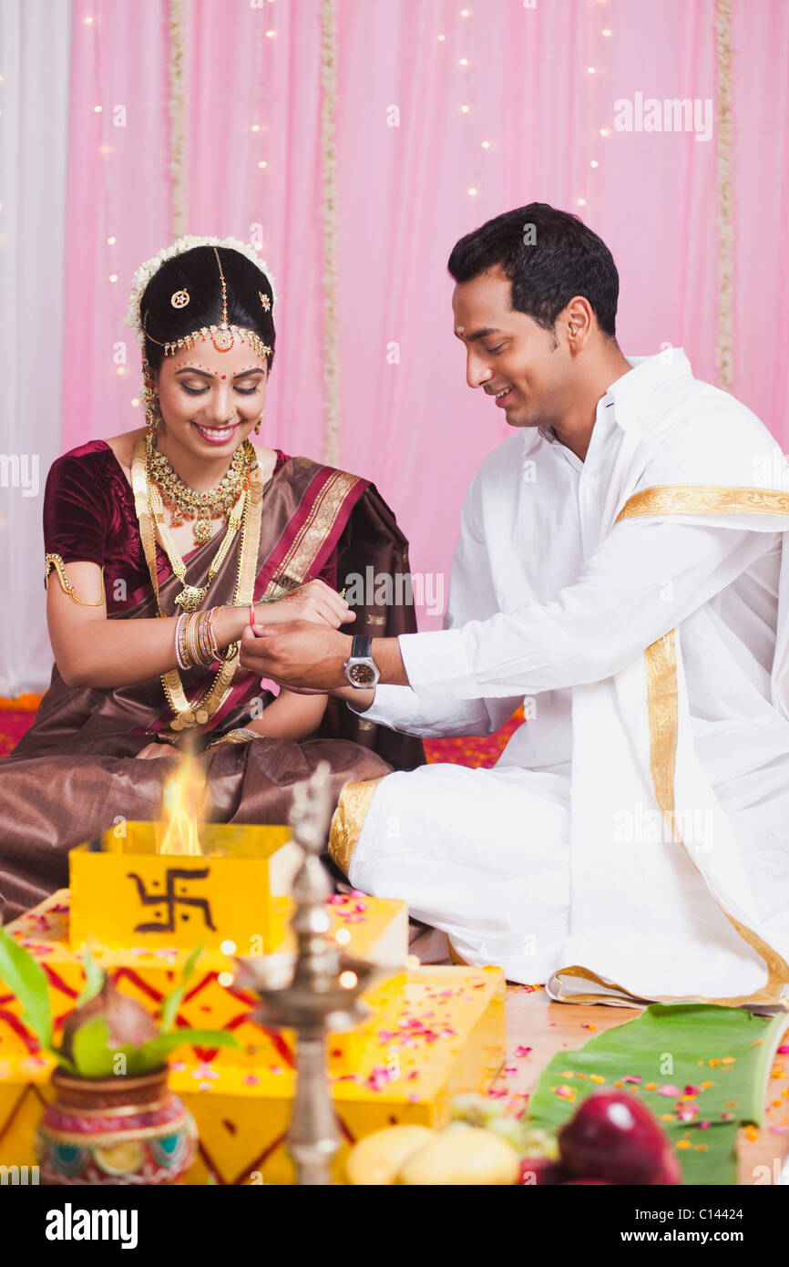 Bridegroom putting holy thread on a bride's wrist Stock Photo - Alamy