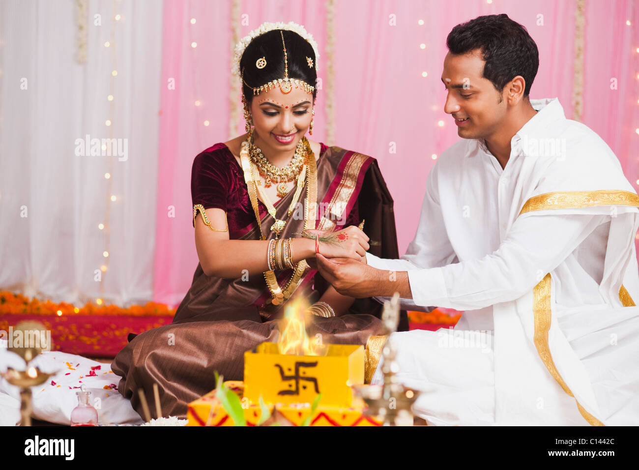 Bridegroom putting holy thread on a bride's wrist Stock Photo - Alamy